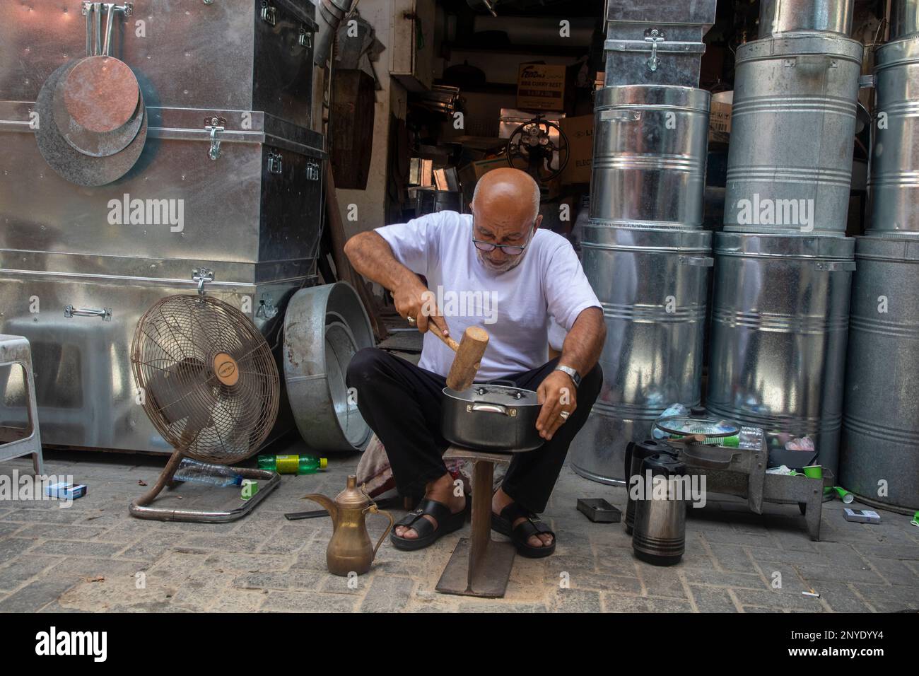 A Bahraini old man repairs crockery outside his shop at the Bab al ...