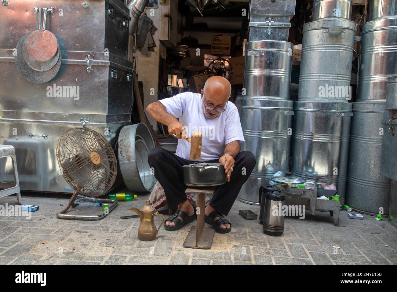 A Bahraini old man repairs crockery outside his shop at the Bab al ...