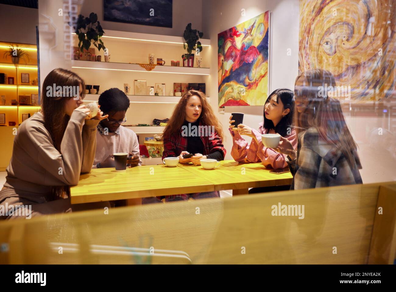 A bunch of young people, girls and guys in a cafe, talking, having fun ...