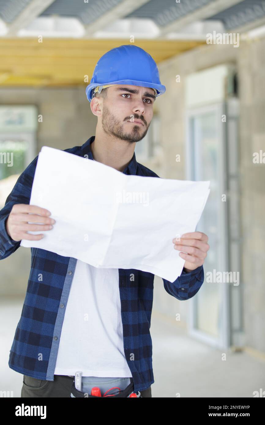 puzzled young builder handyman examining room and planning renovation ...