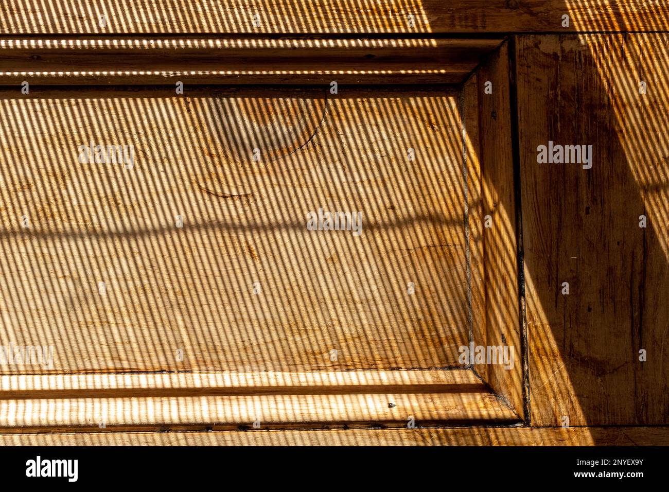 Sunflight falling through blinds onto a wooden shutter. Vertical ...