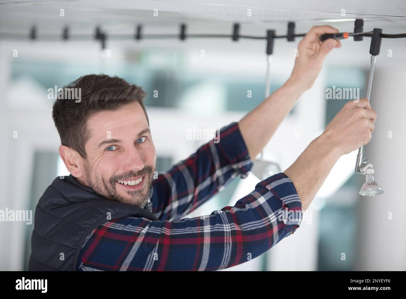 happy male electrician is repairing ceiling light Stock Photo - Alamy
