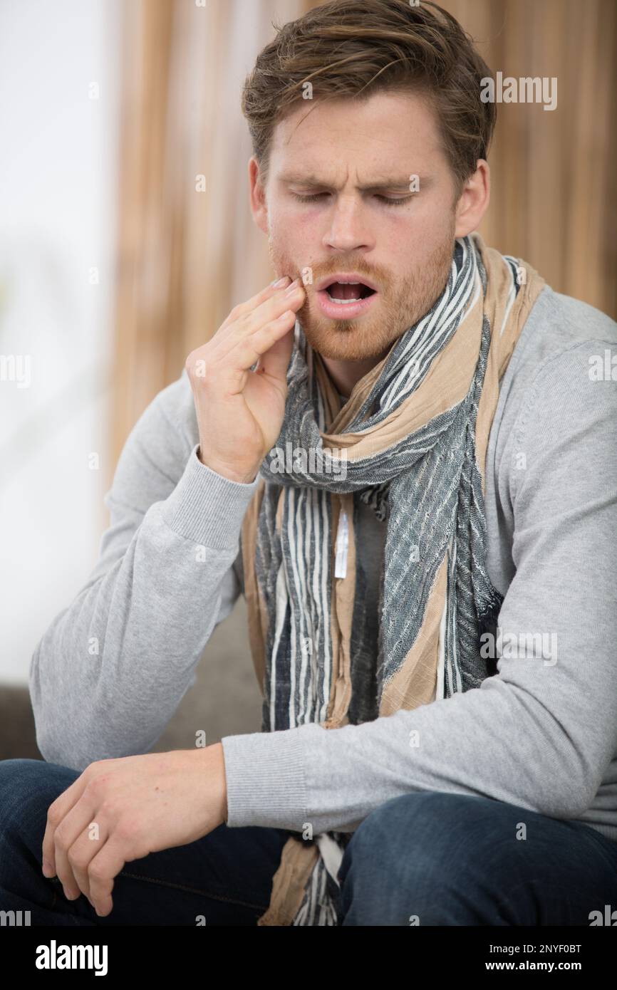 unhealthy suffering man holds his cheek Stock Photo - Alamy