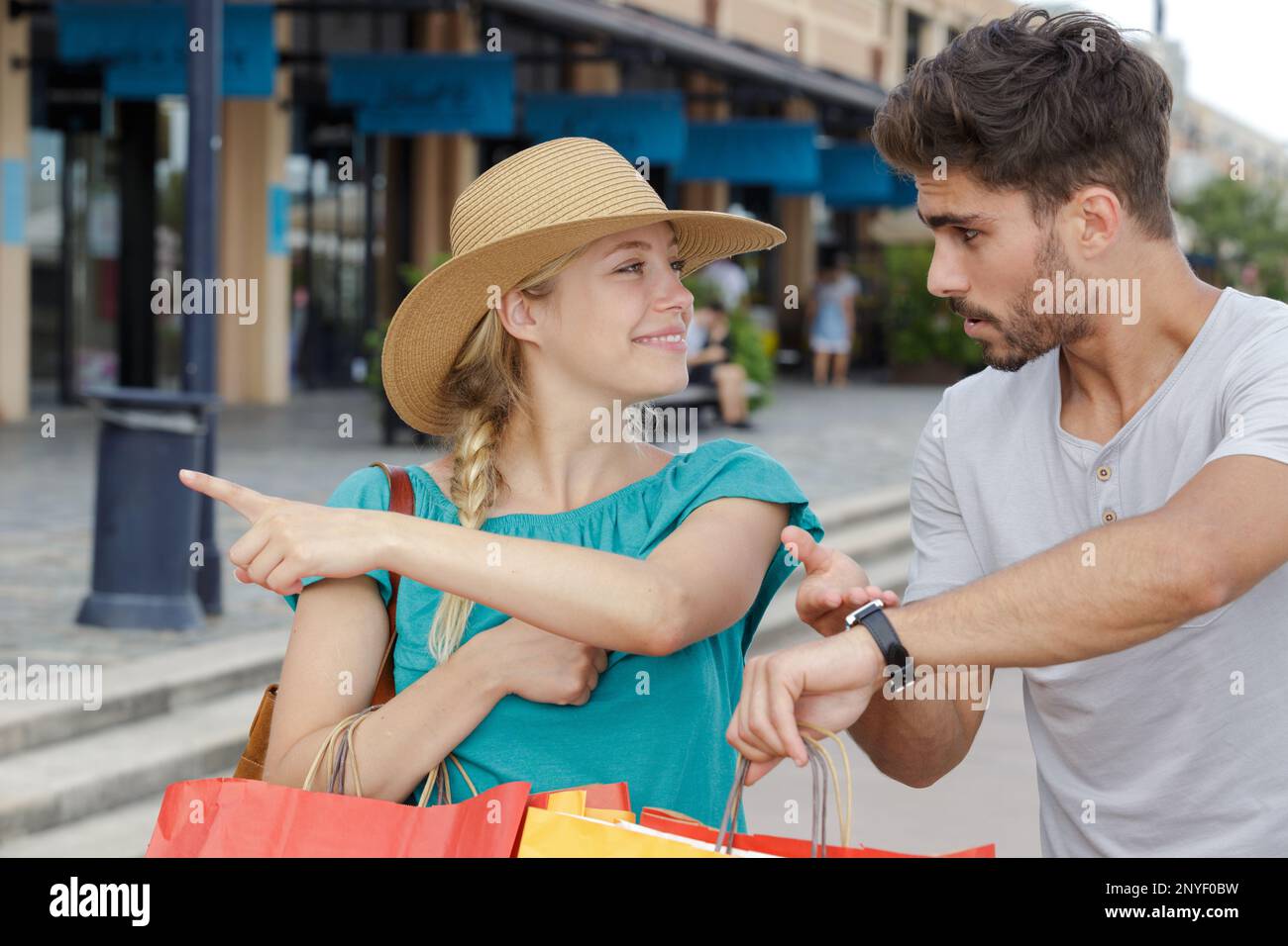man looking at watch as girlfriend want to continue shopping Stock ...