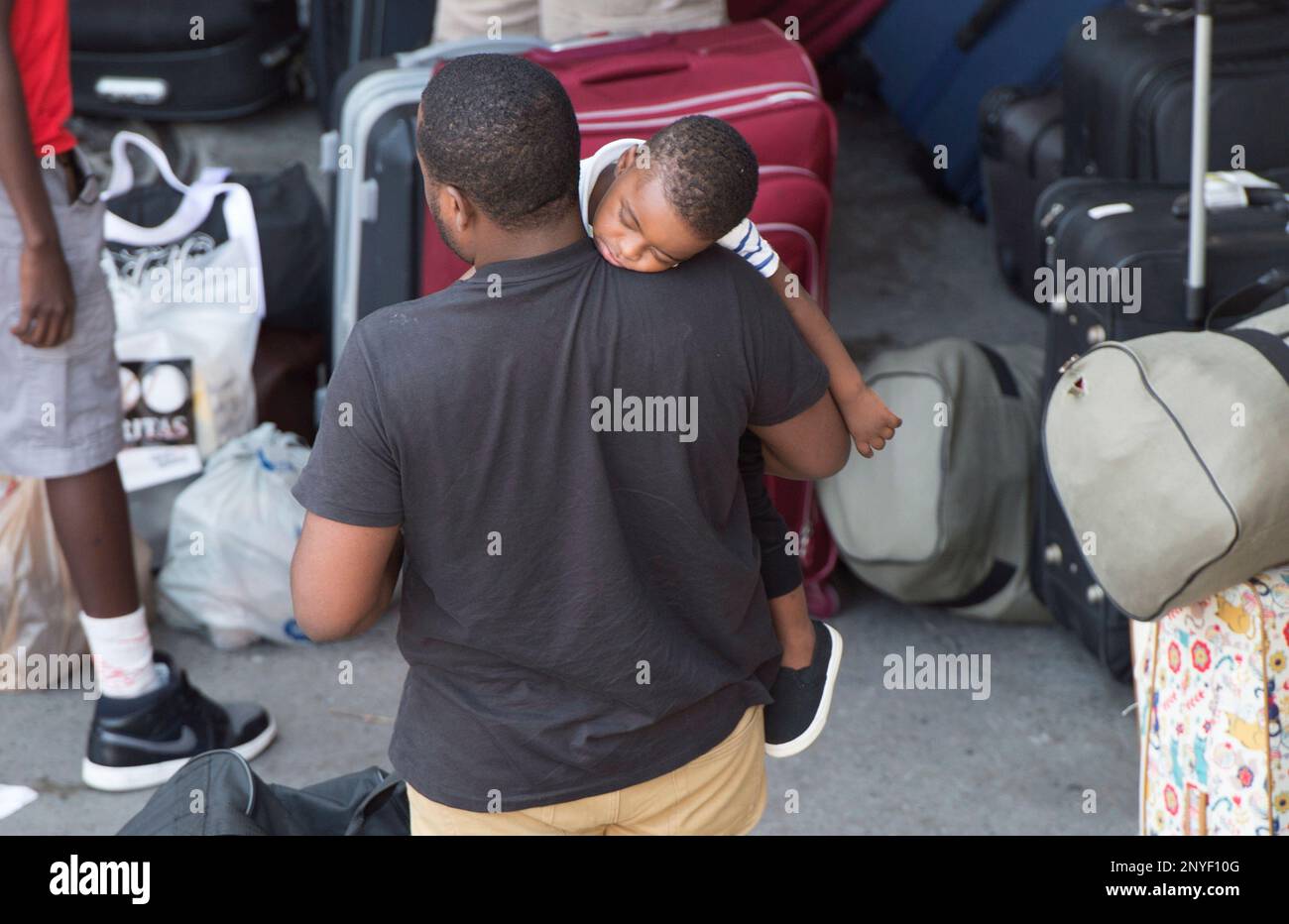 A young boy sleeps in a man's arms as asylum seekers line up to enter ...
