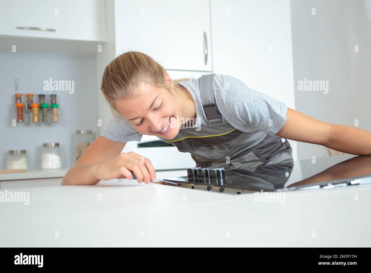 female engineer fitting new kitchen hob Stock Photo - Alamy