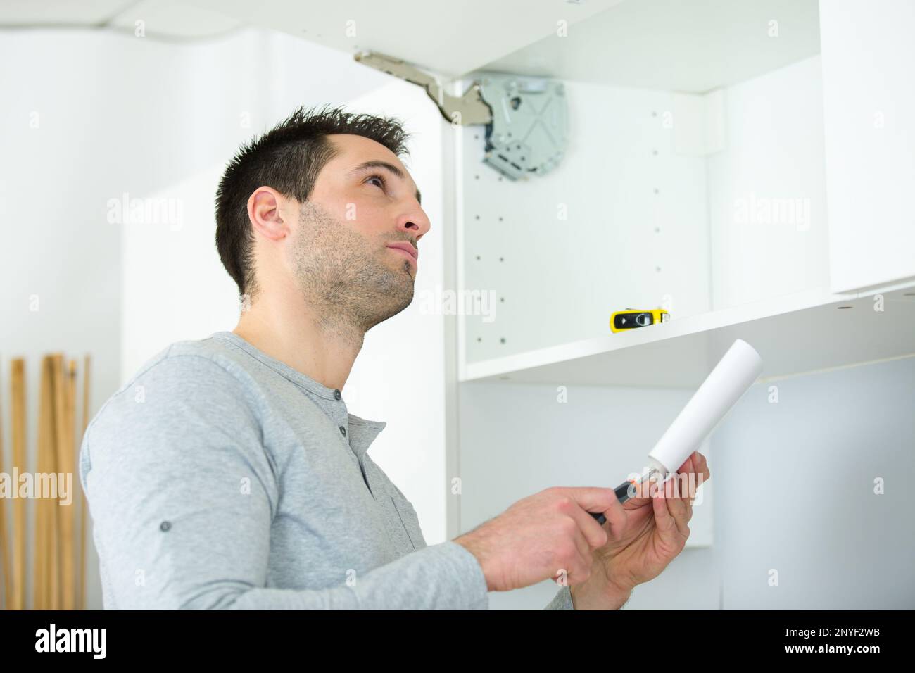 a worker installing kitchen cupboard Stock Photo - Alamy