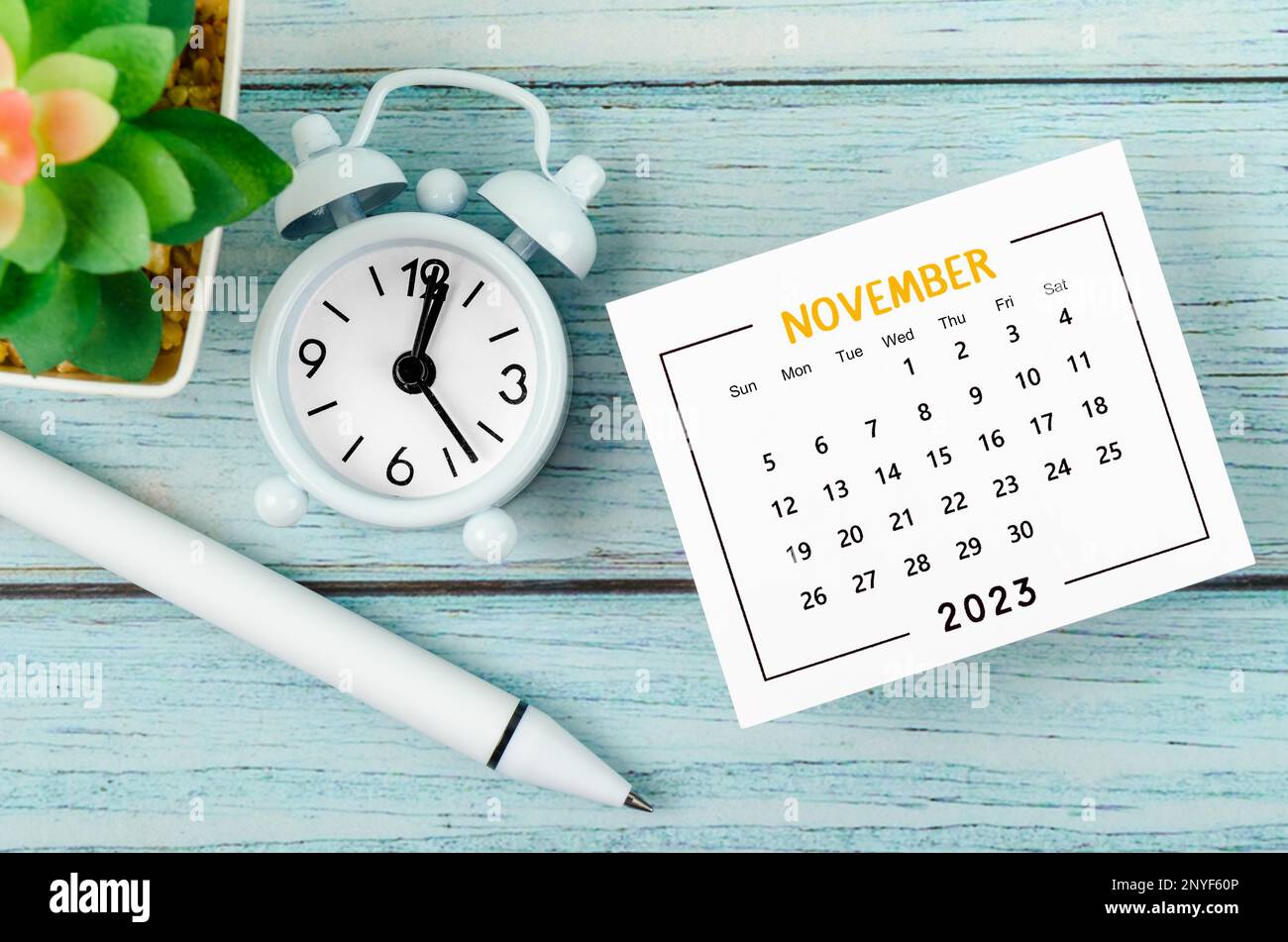 November 2023 Monthly calendar year and alarm clock with pen on blue ...