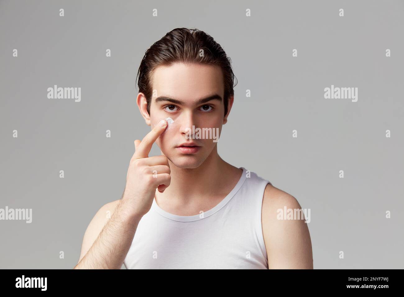 Clear skin. Portrait of young handsome boy applying moisturizing face ...