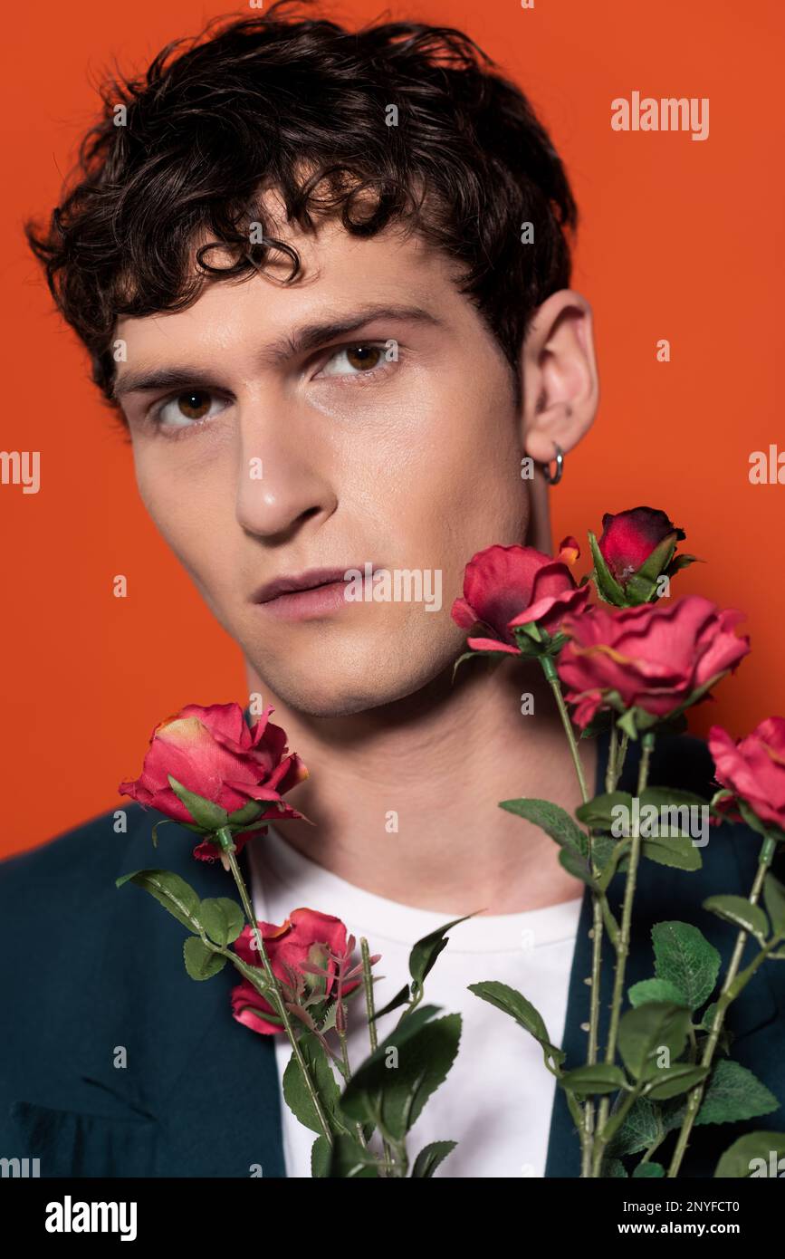romantical young man posing near roses isolated on red,stock image ...