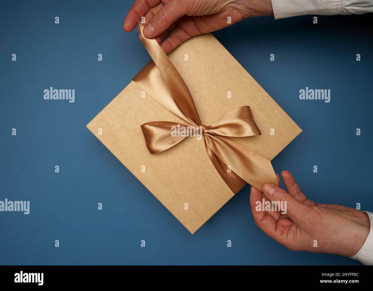 paper gift box with ribbon on isolated blue background unpacking by ...