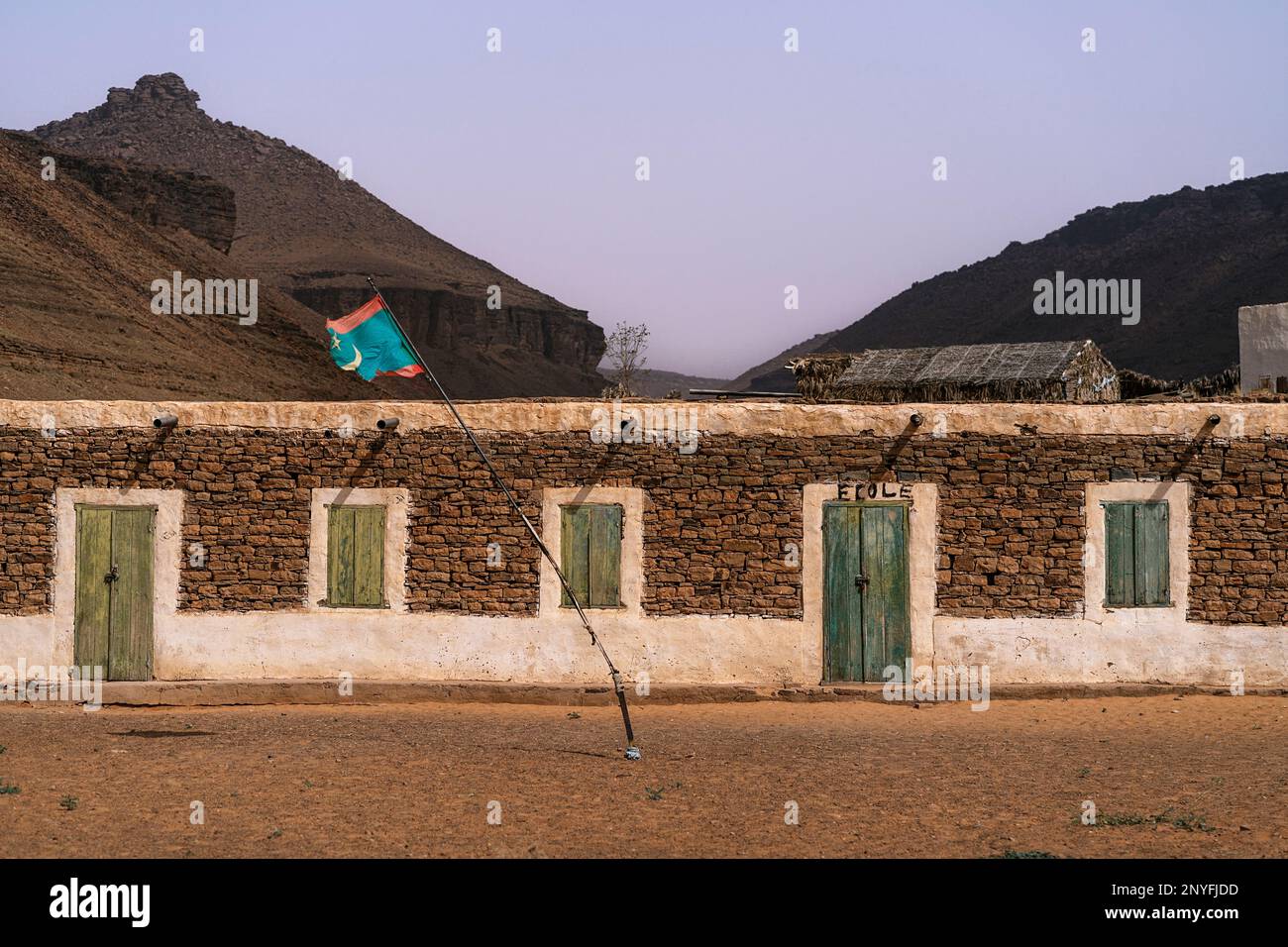 Aged stone building with shabby walls and windows located near flag of ...