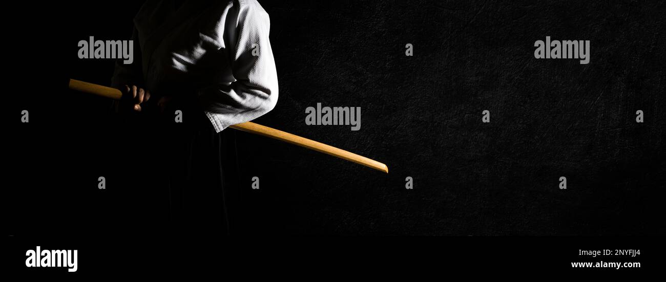 A person in black hakama standing in fighting pose with wooden sword ...