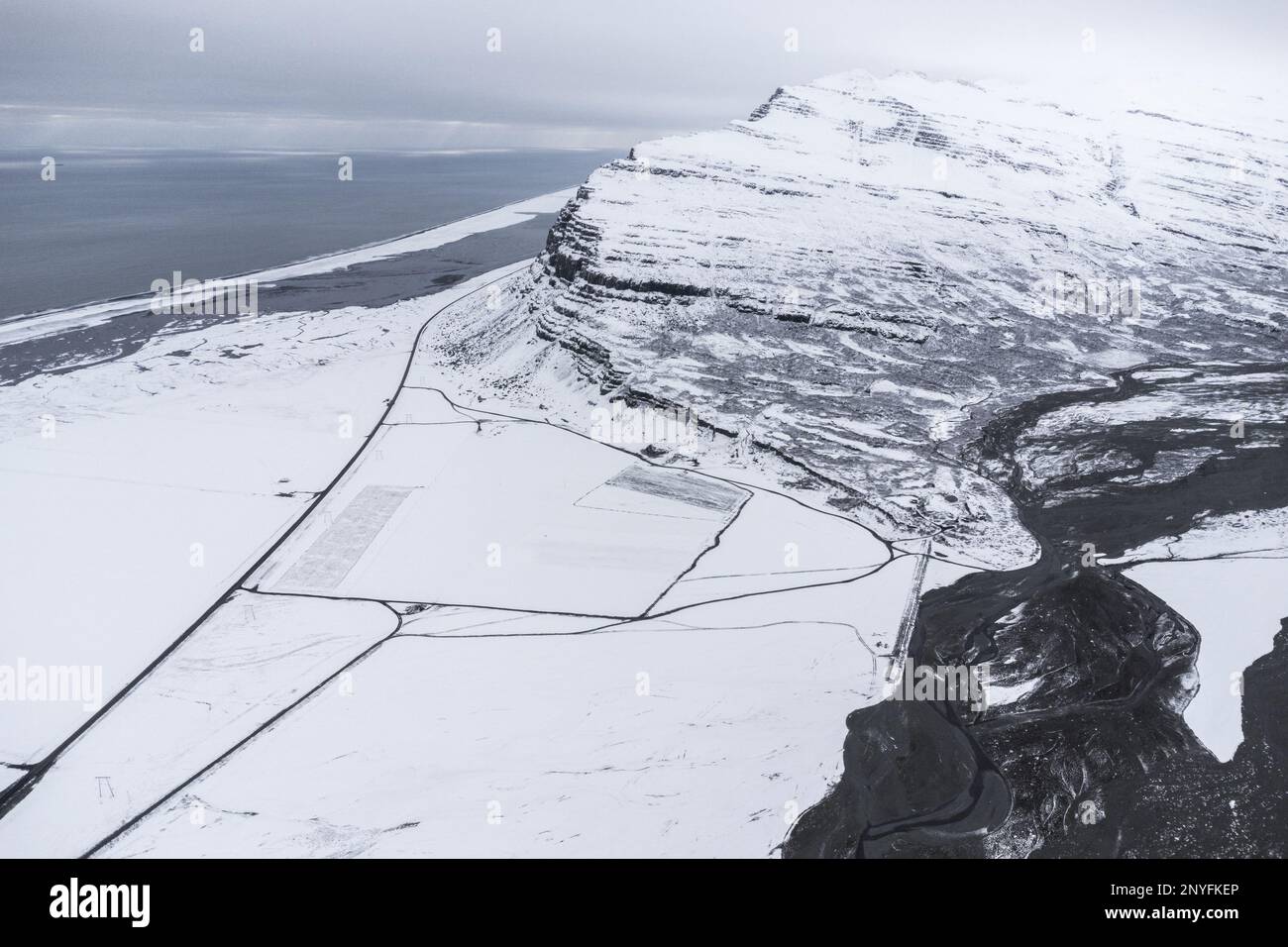 From above drone view of river estuary covered in snow with road and ...