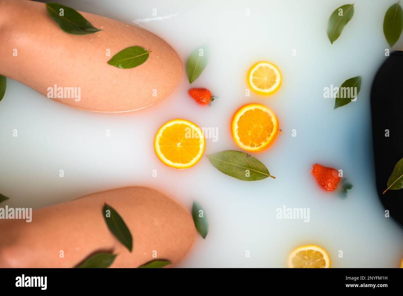 Top view of crop anonymous female in black swimsuit taking milk bath ...