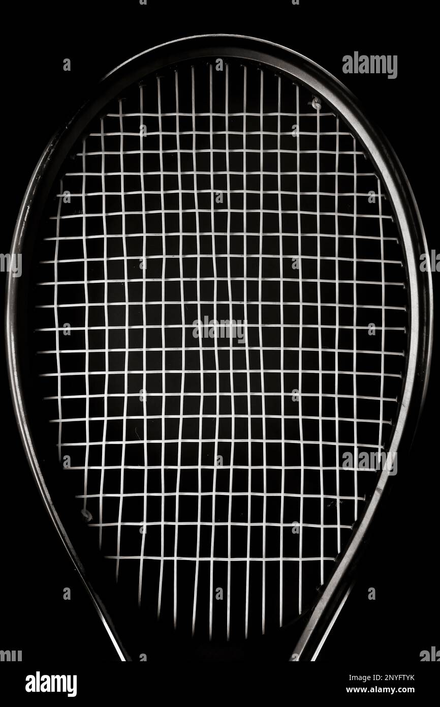 Close up view in black and white of the top of a tennis racket lit by ...