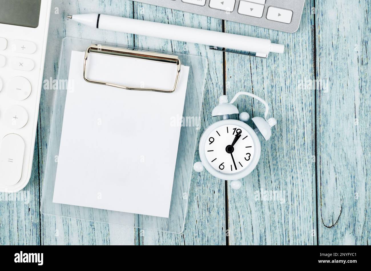 Small white paper blank page on clip board, alarm clock and calculator ...