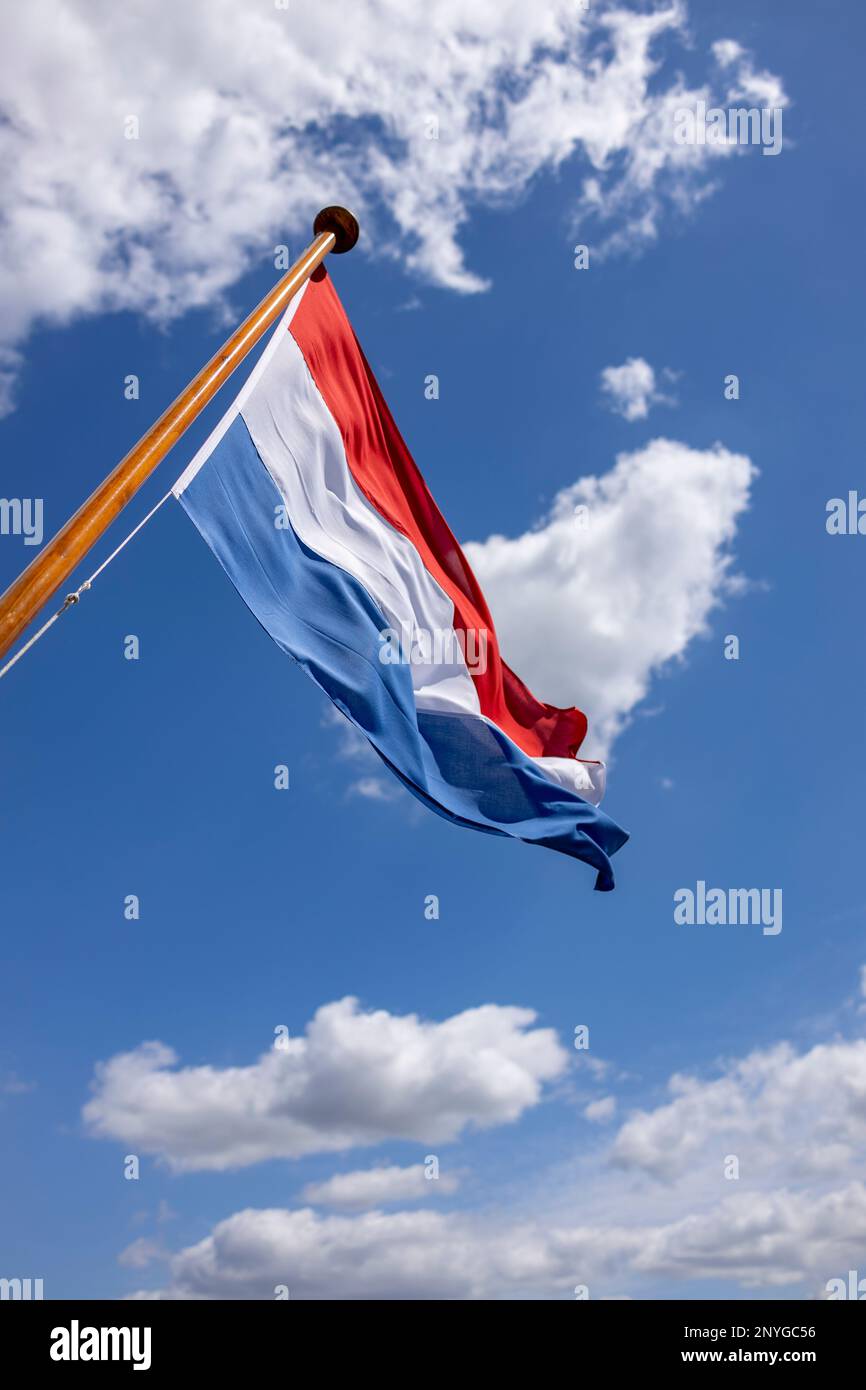Brightly lit tricolor of Dutch national flag blowing in a strong wind ...