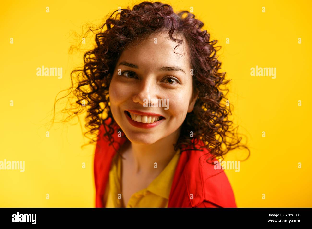 Studio shot of positive and the smiling pretty female. Curly girl in ...