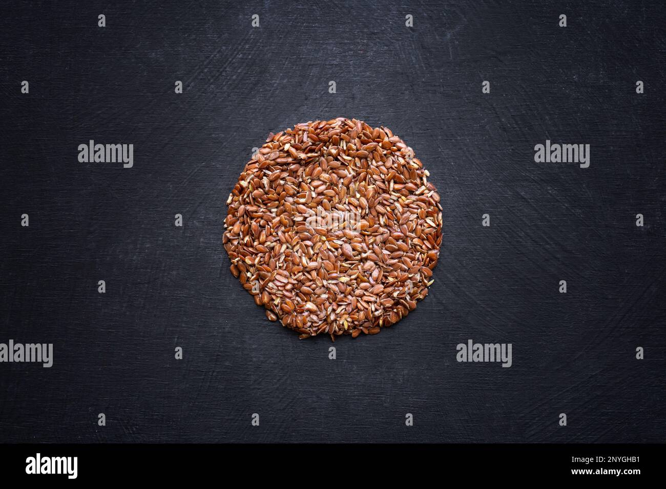 A top view of linen seeds shaped as a circle on a black background ...