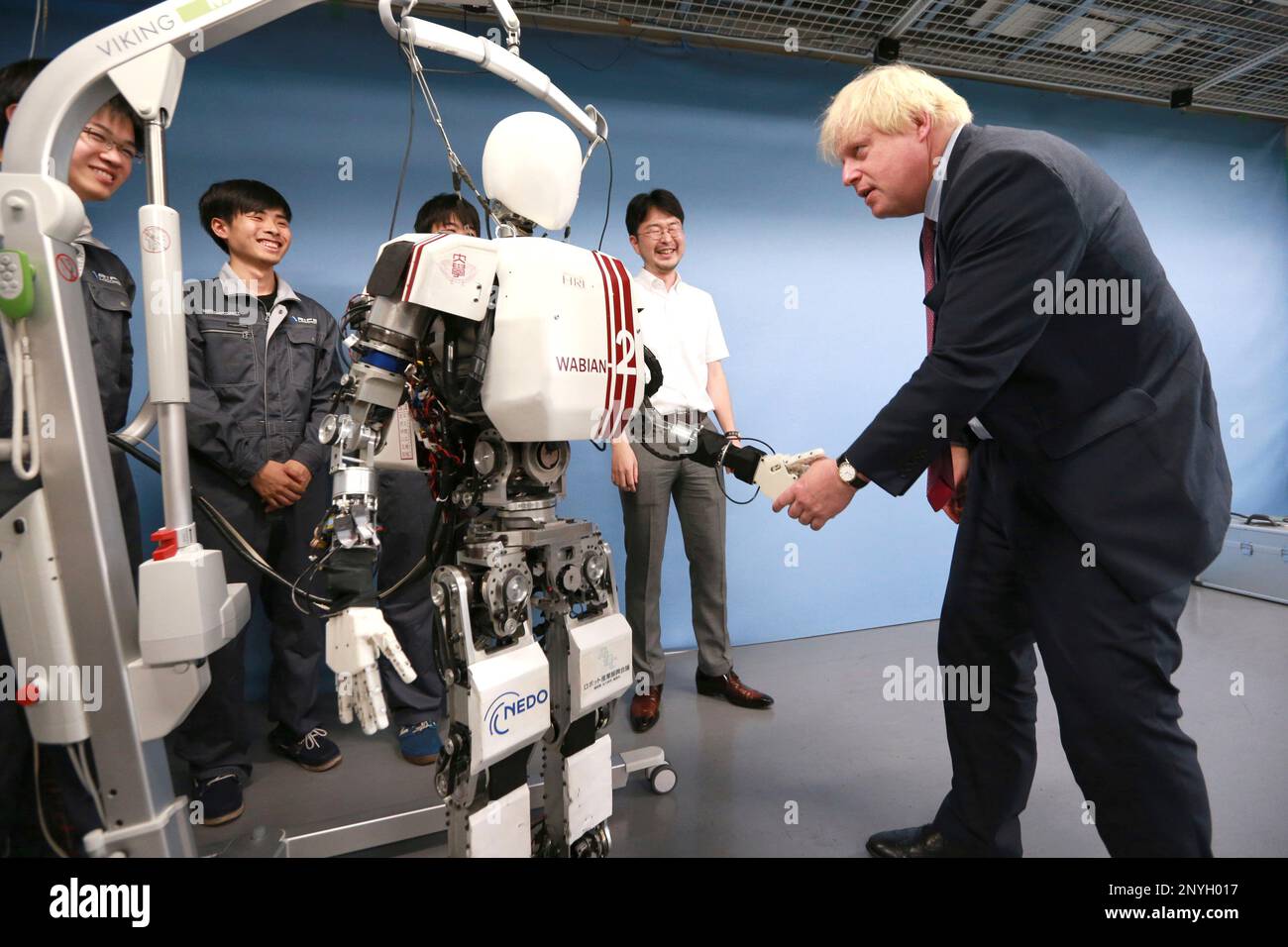 British Foreign Minister Boris Johnson (R) shakes hands with a humanoid ...