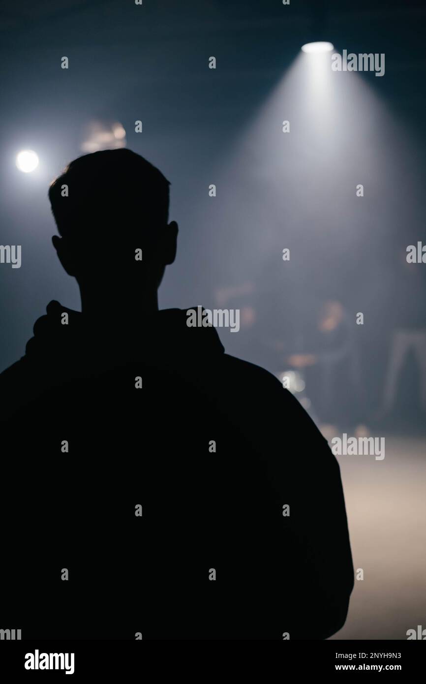 The silhouette of a person. In the background are spotlights. In the ...