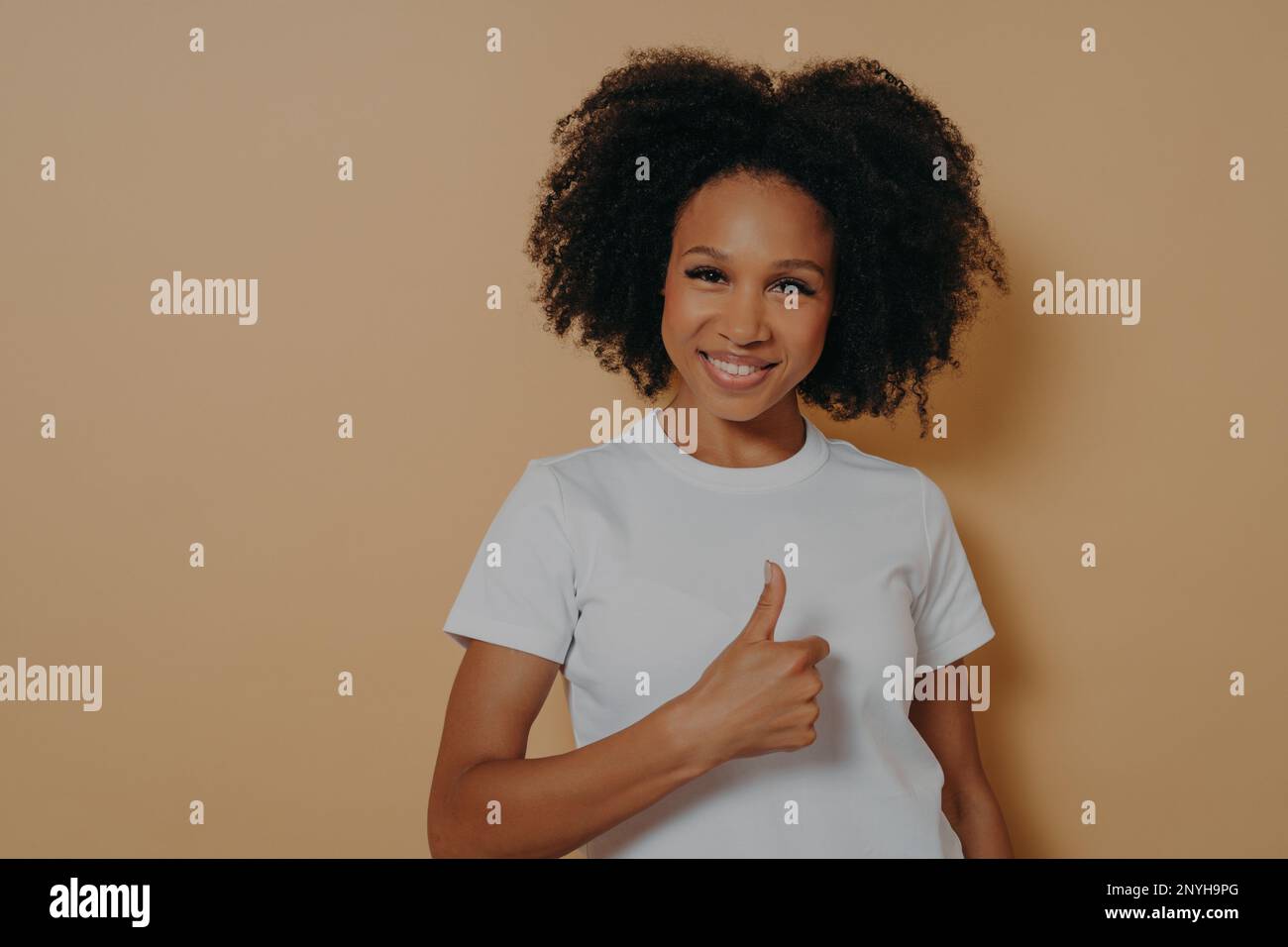Cheerful positive young african woman showing success gesture, thumb up ...