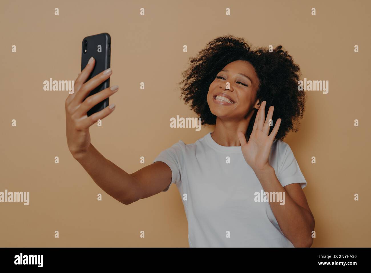 Positive happy mixed race woman waving with hand at camera during video ...