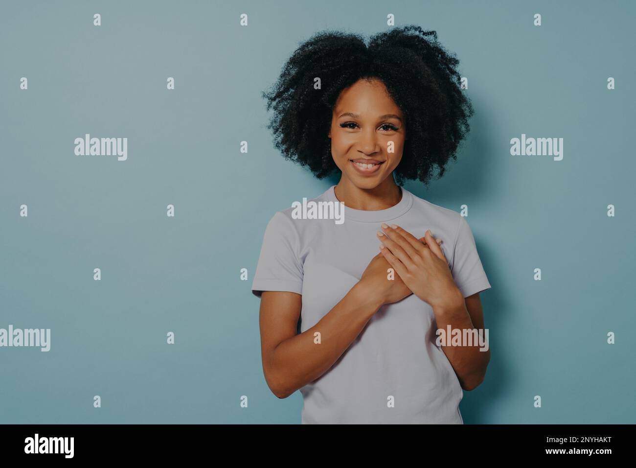 Grateful hopeful happy black woman holding hands on chest, satisfied ...