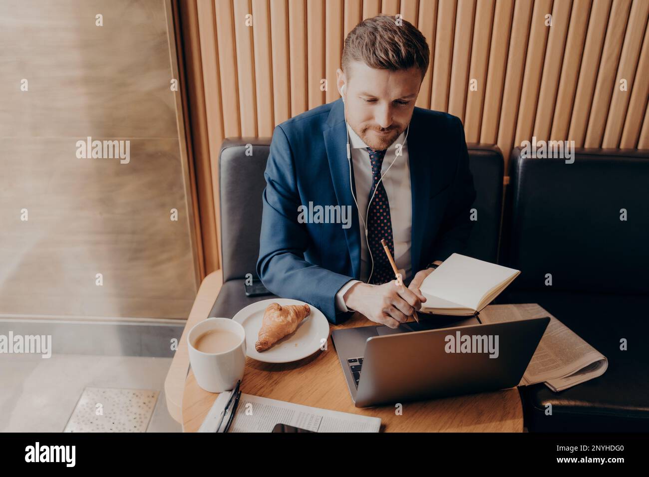 Male business executive in blue suit in earphones studying online ...
