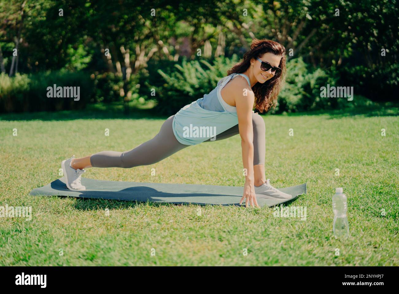 Flexible brunette girl in sportswear does exercises on fitness mat ...