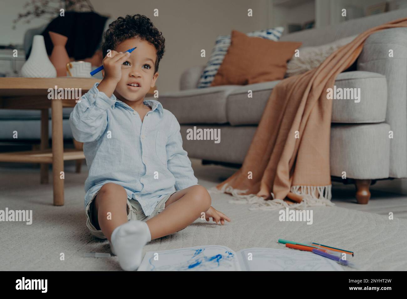 Mixed race toddler in casual clothes sitting on floor next to coffee ...