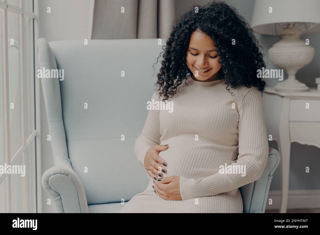 Happy pregnancy. Pretty mixed race woman with curly hair in white ...