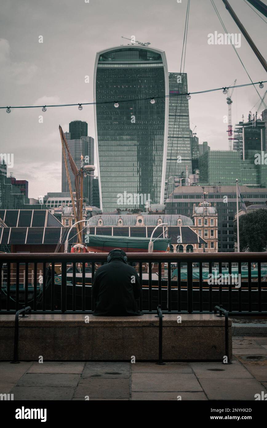 A man sitting alone on a bench, looking out at a stunning London ...