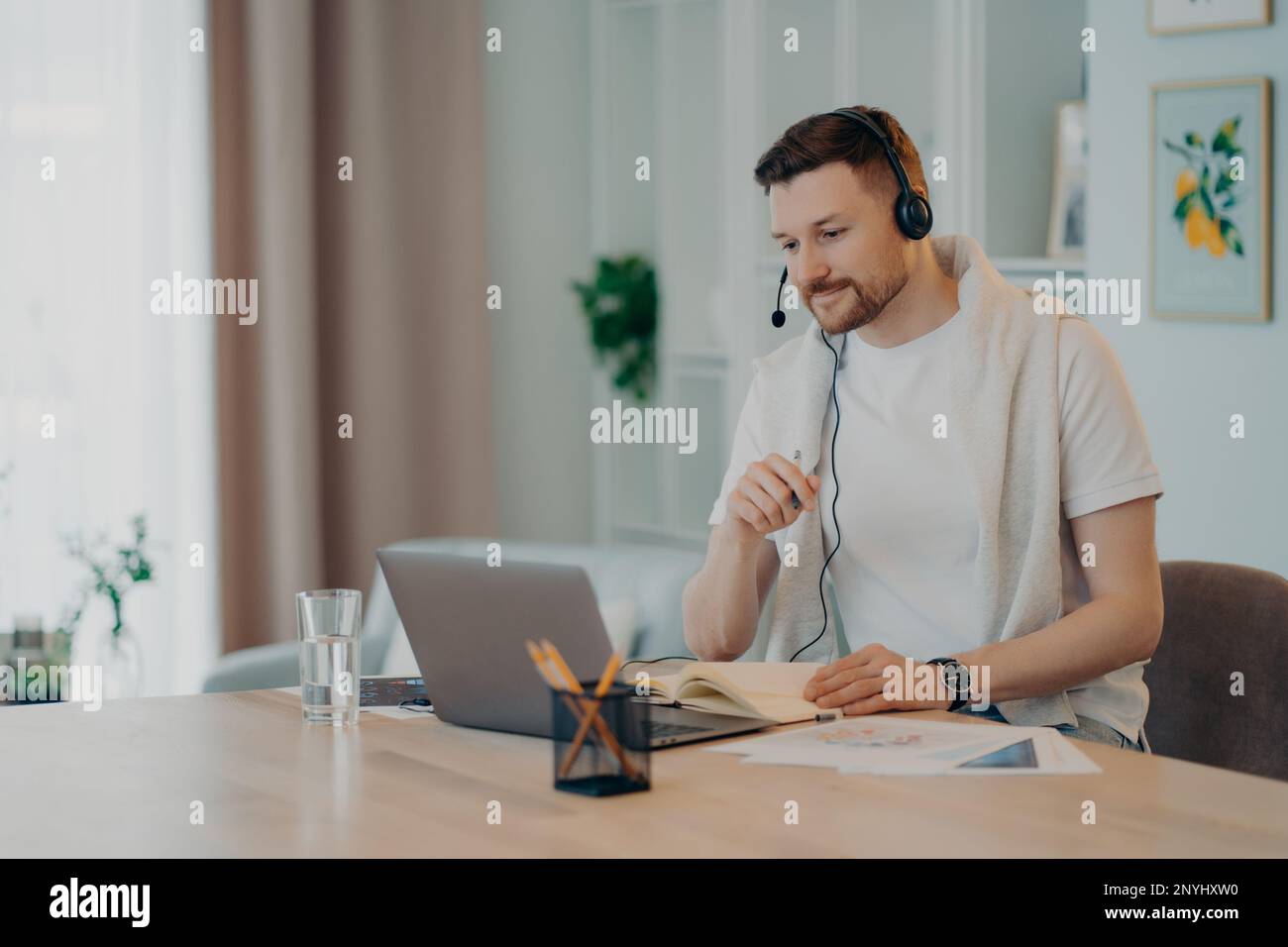 European male student learns foreign languages online has video lesson uses modern headset ...