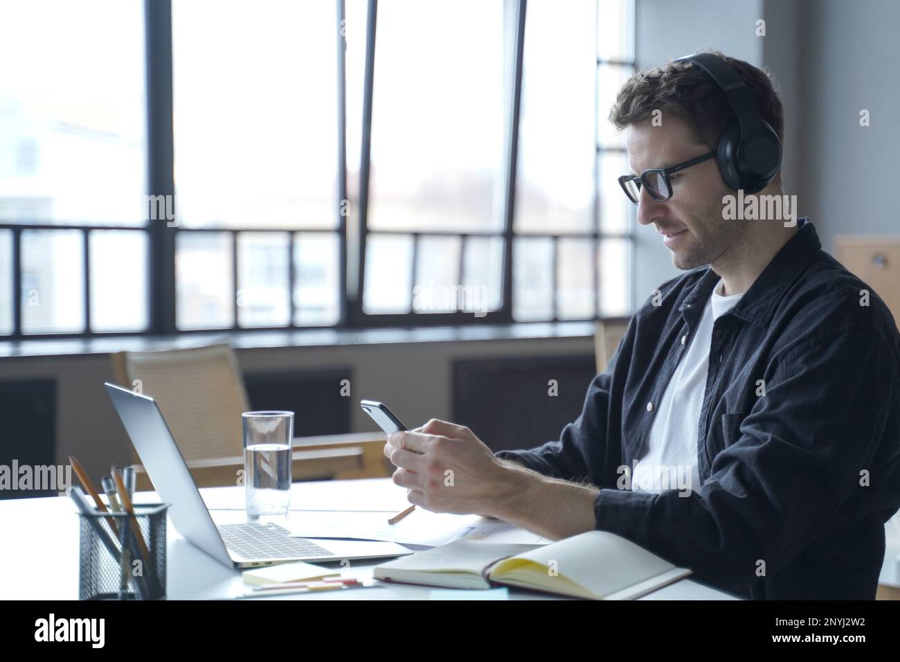 Young german male freelancer in headphones and glasses looking at ...