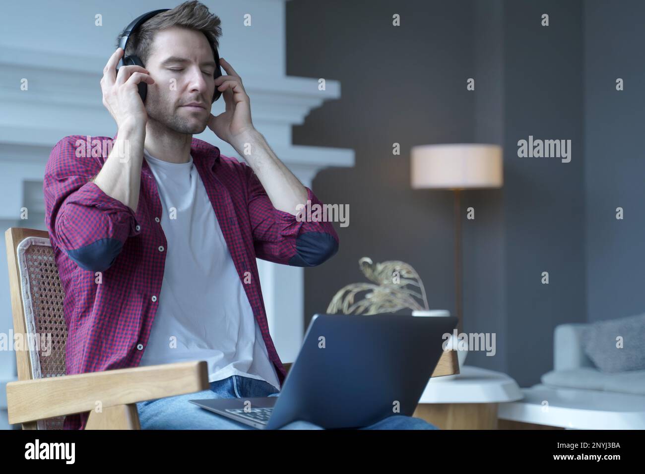 Young austrian guy sitting on wooden wicker chair with open laptop on ...