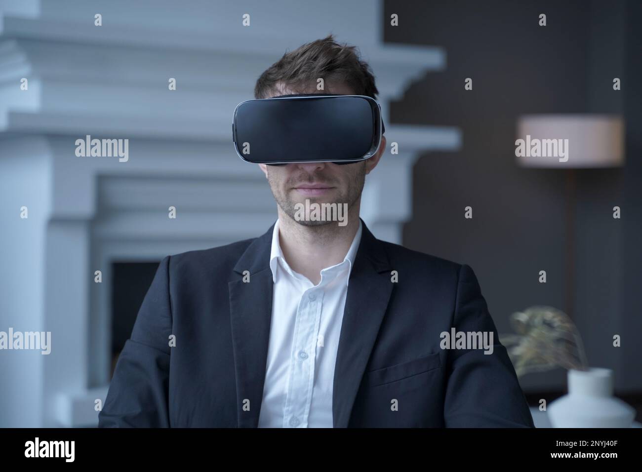 Serious businessman in black suit in VR headset on head working on ...