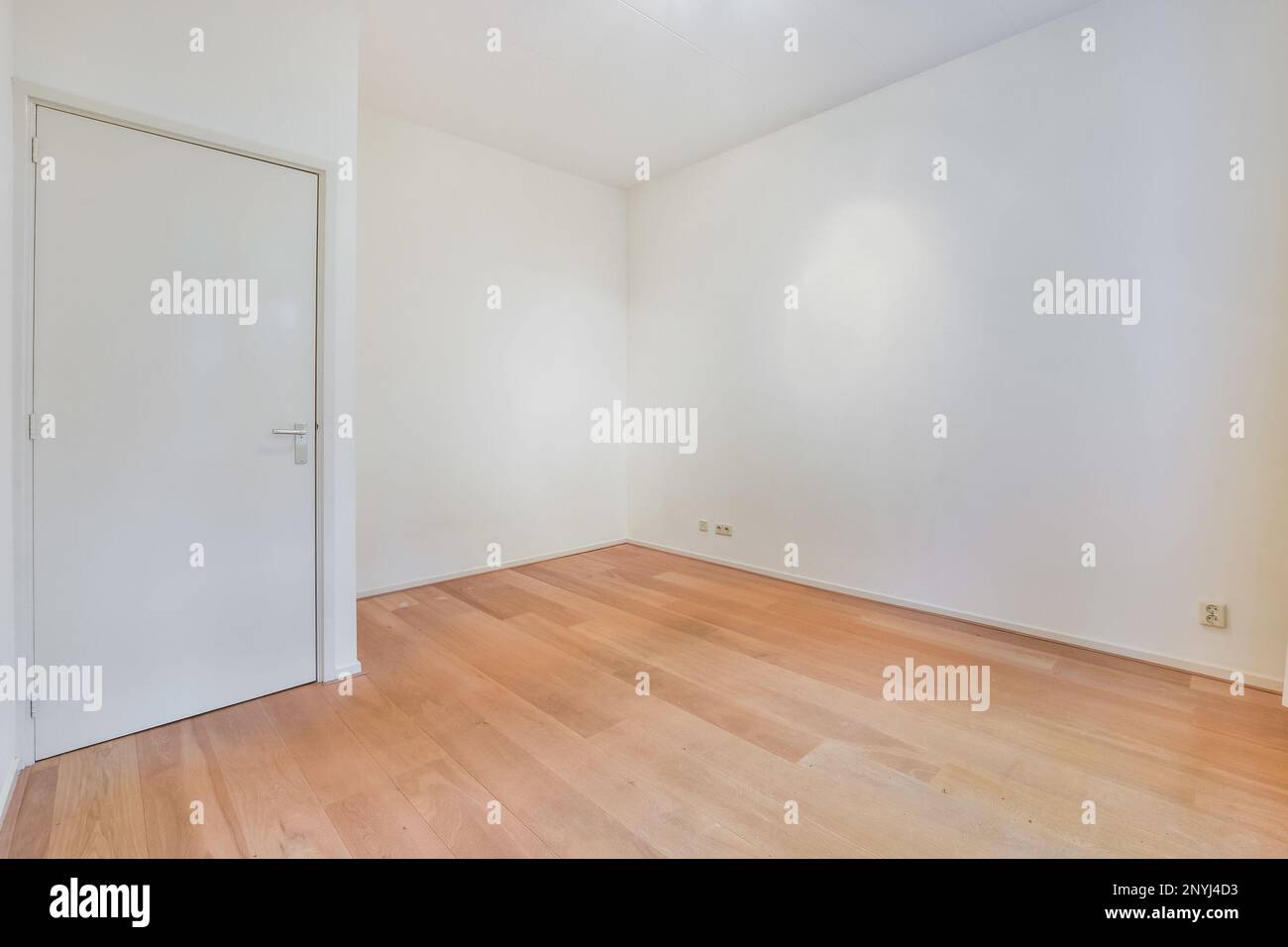 an empty room with wood floors and white walls, there is a door leading ...