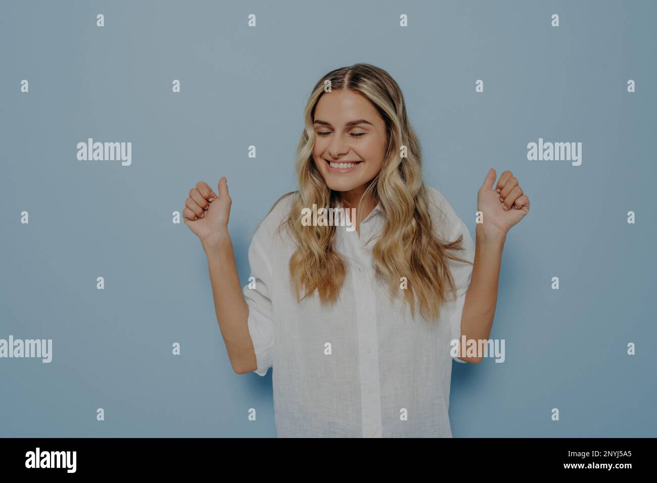 Excited young blonde girl filled with joy cheering with both hands in ...