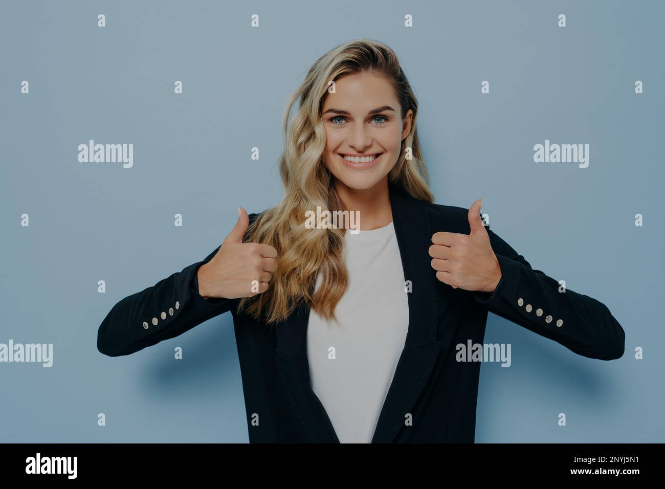 Excellent job gesture. Cheerful girl with blonde wavy hair looking at ...