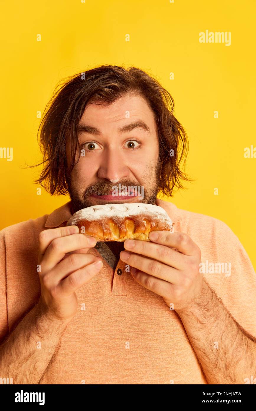 Half-length portrait of bearded man looking at camera and tasting sugar ...