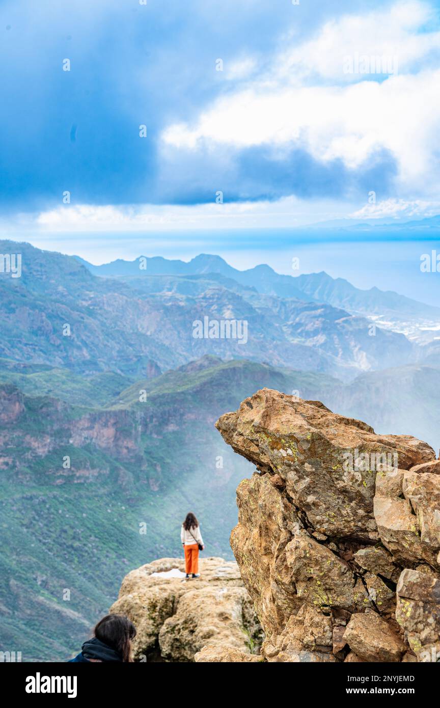 Aerial perspective shot of female hiker in standing posture on top of ...