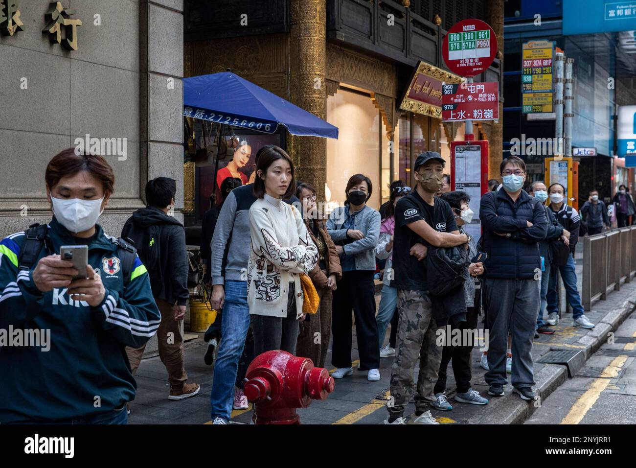 People wearing masks and others without masks line up for public ...