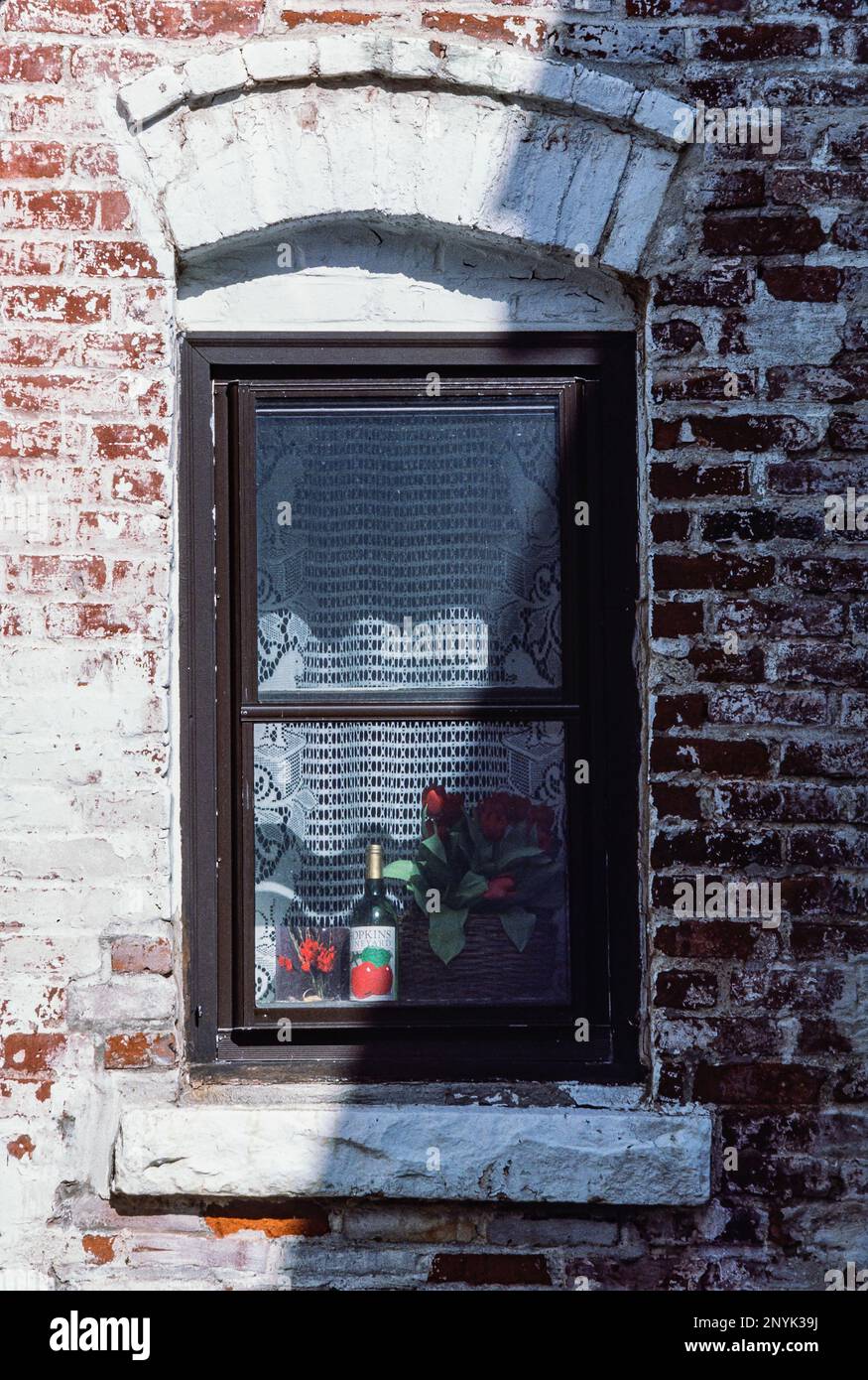Brickwork arch frames window with granite sill, lace curtains and ...