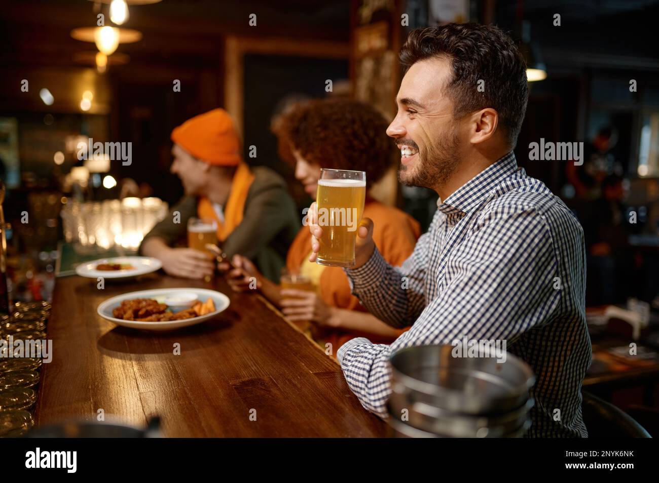 Happy smiling man sitting at sports bar counter desk looking at camera ...