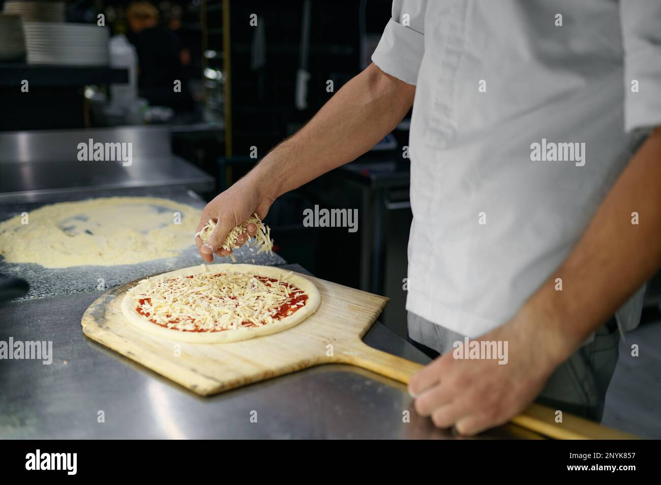 Pizza preparation process with closeup chef hands sprinkling cheese ...