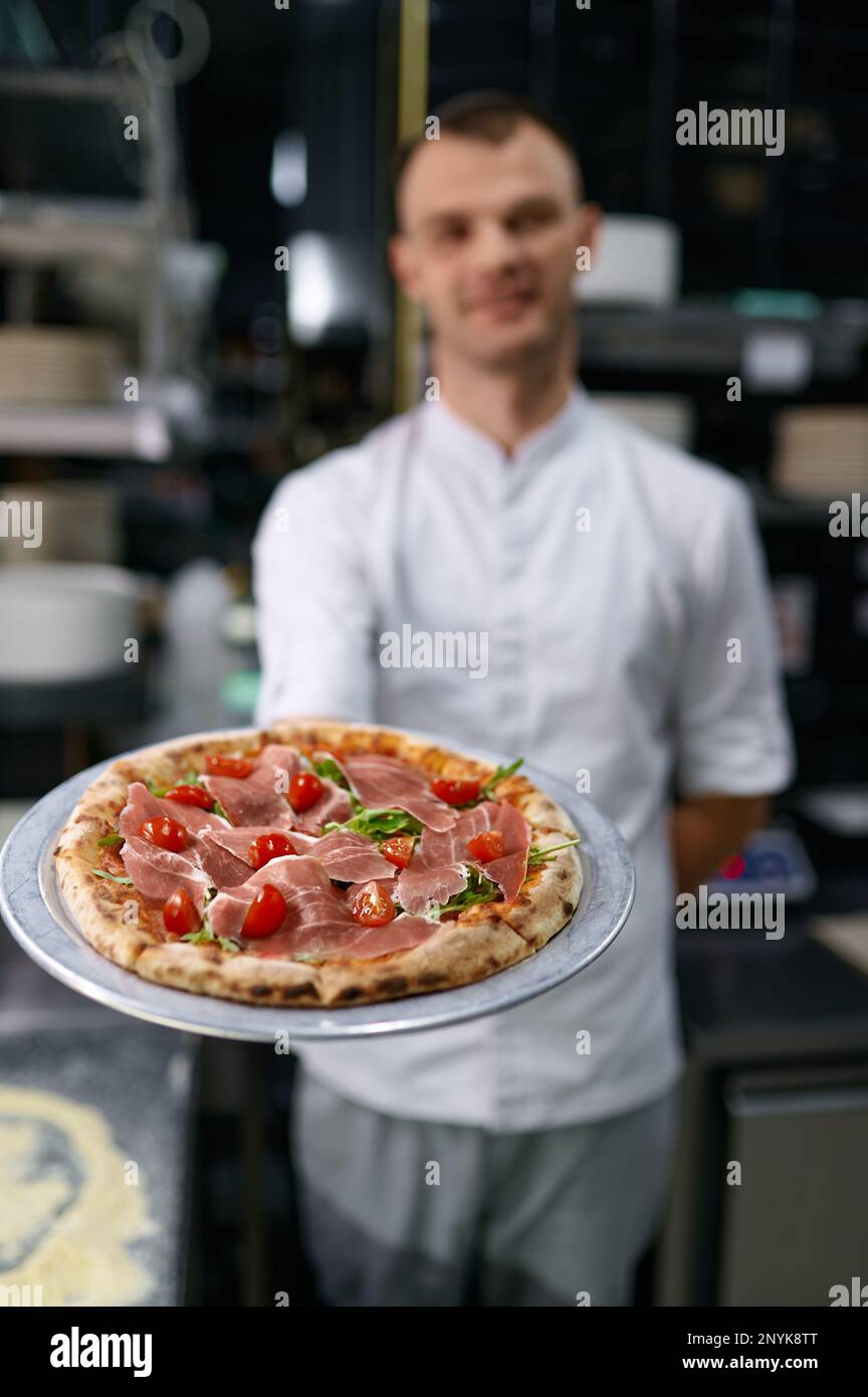 Portrait of male pizzaiolo presenting freshly cooked pizza Stock Photo ...