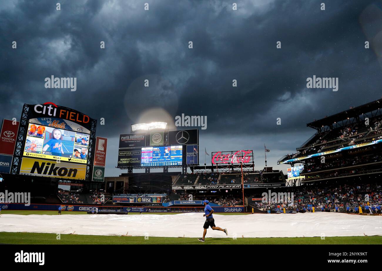 A member of the New York Mets grounds crew runs along the field after ...