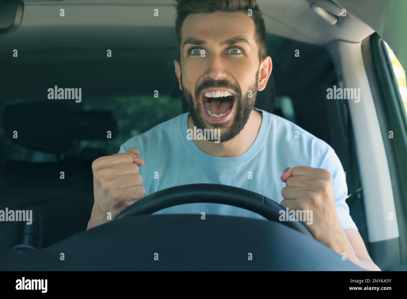Stressed angry man in driver's seat of modern car, view through ...